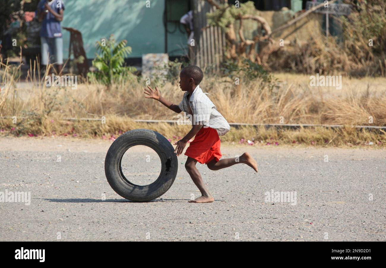A young boy rolls a used tire on the streets of Highfield in Harare ...