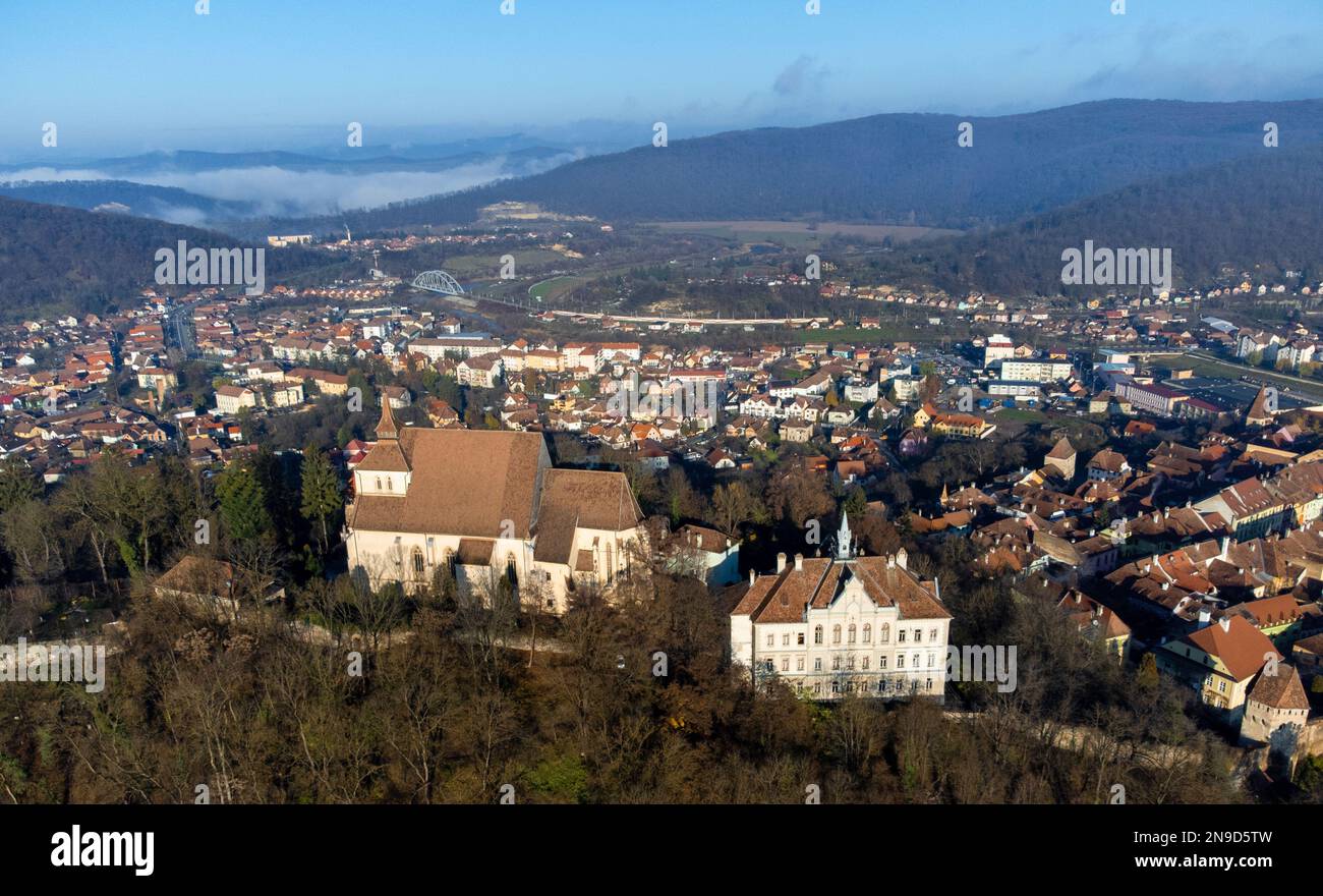 An aerial shot of Sighisoara fortress in Romania with urban town in ...