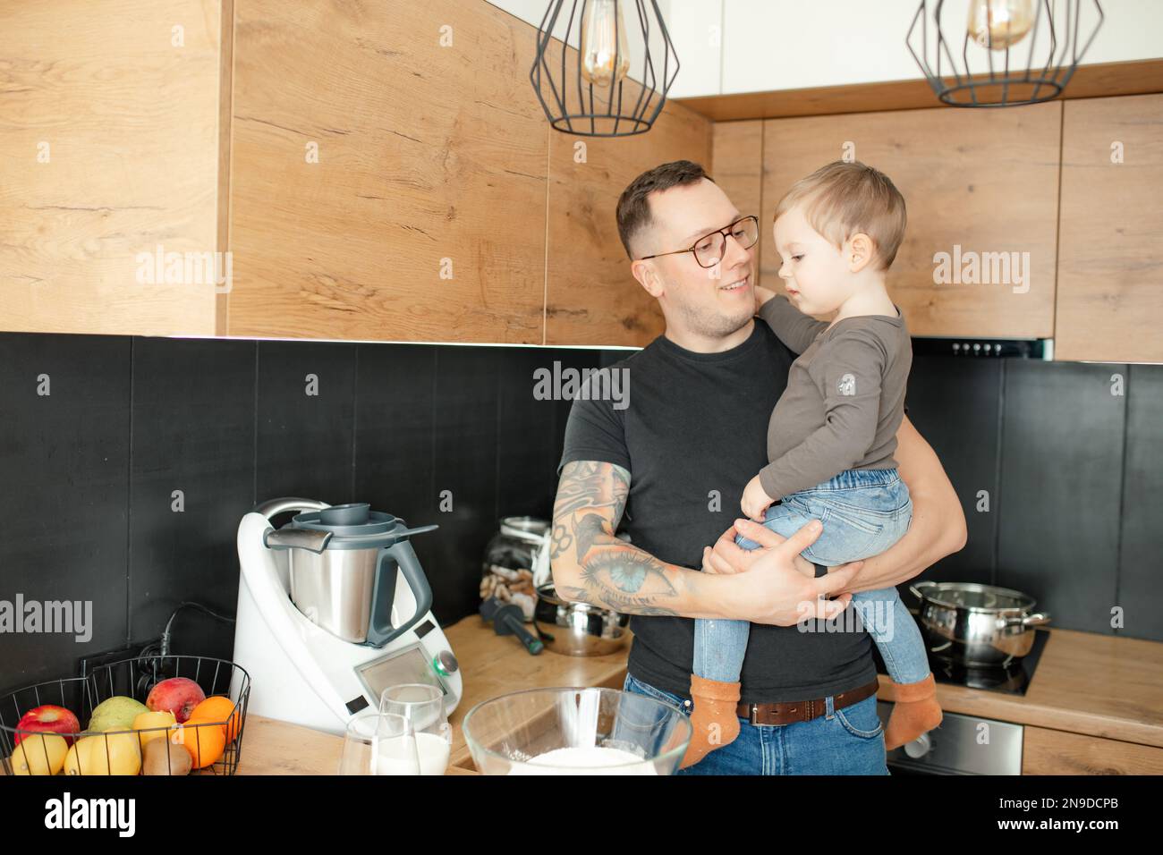 Kind, smiling and careful father in glasses holding little blond son in ...