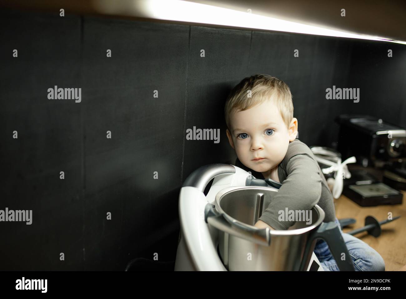 Cute blond little toddler boy mix food with hand in steel blender, food ...