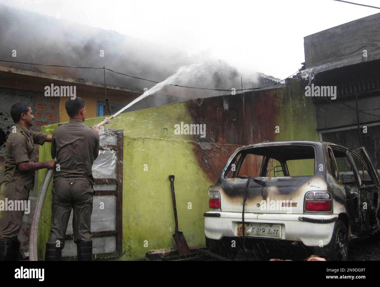 Indian fire fighters try to extinguish on houses which were set ablaze ...