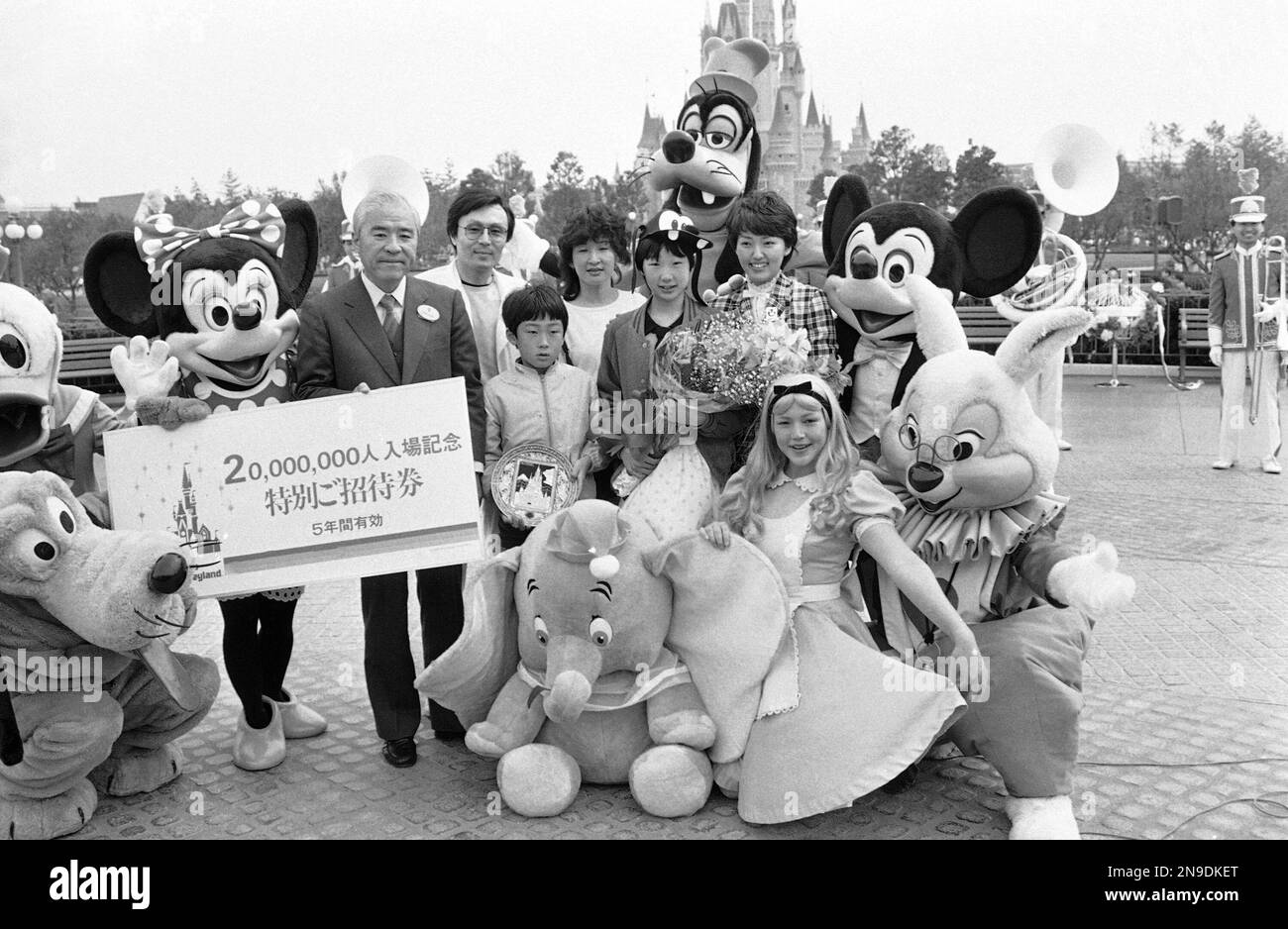 Yuko Yamamoto, with a Mickey Mouse cap and flowers, is congratulated by ...