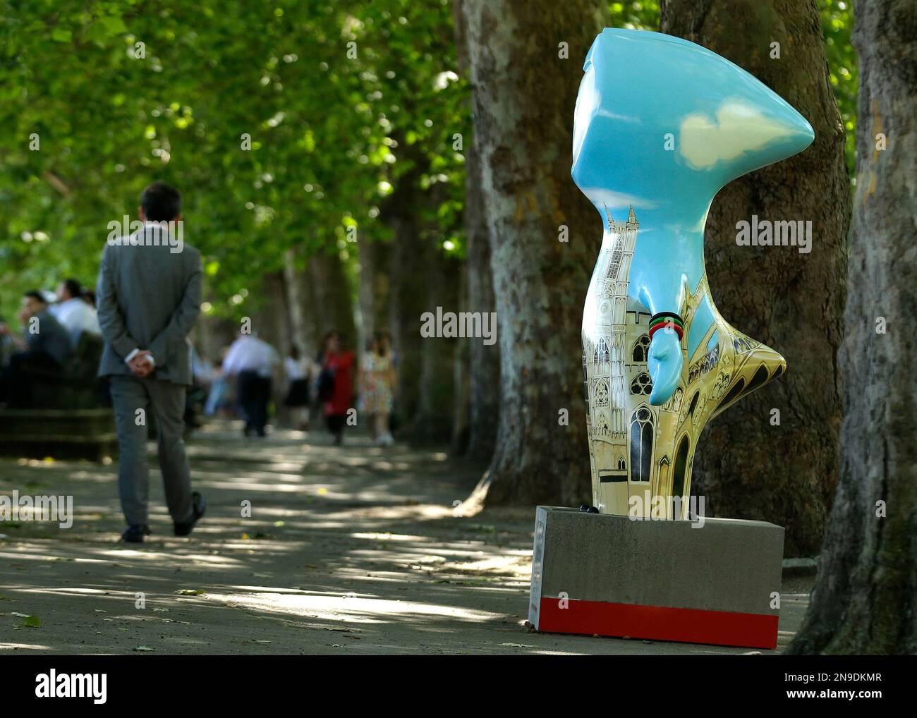 Pedestrians stroll past an Olympic mascot statue painted to look like ...