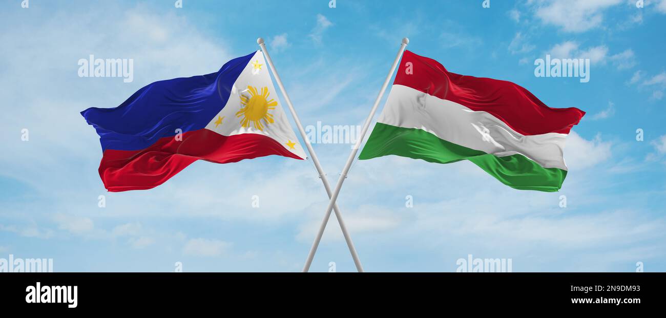 two crossed flags Hungary and Philippines waving in wind at cloudy sky ...