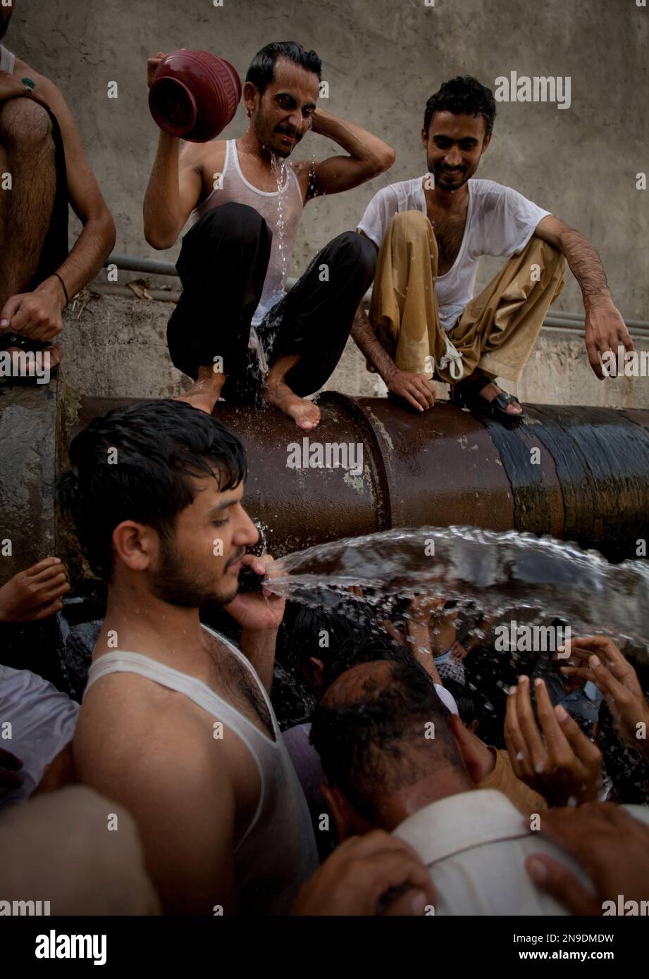 Pakistanis use a water pipe to cool themselves as temperature rises to ...