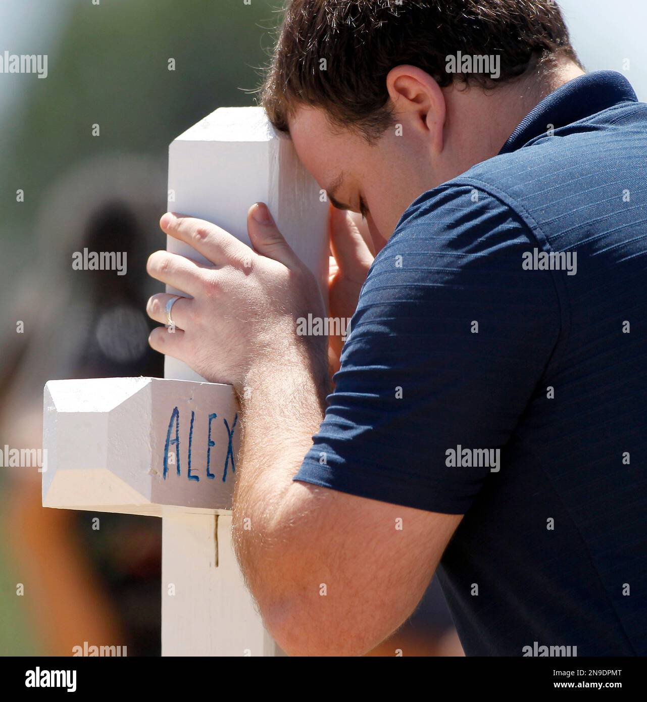 Travis Hirko pauses at a cross brought by Greg Zanis with the name of a ...