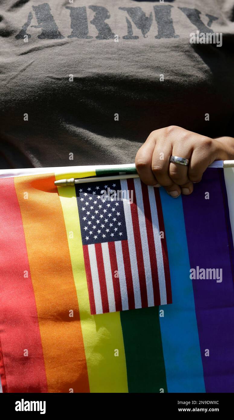 A Soldier wearing an Army t-shirt holds flags during the gay pride ...