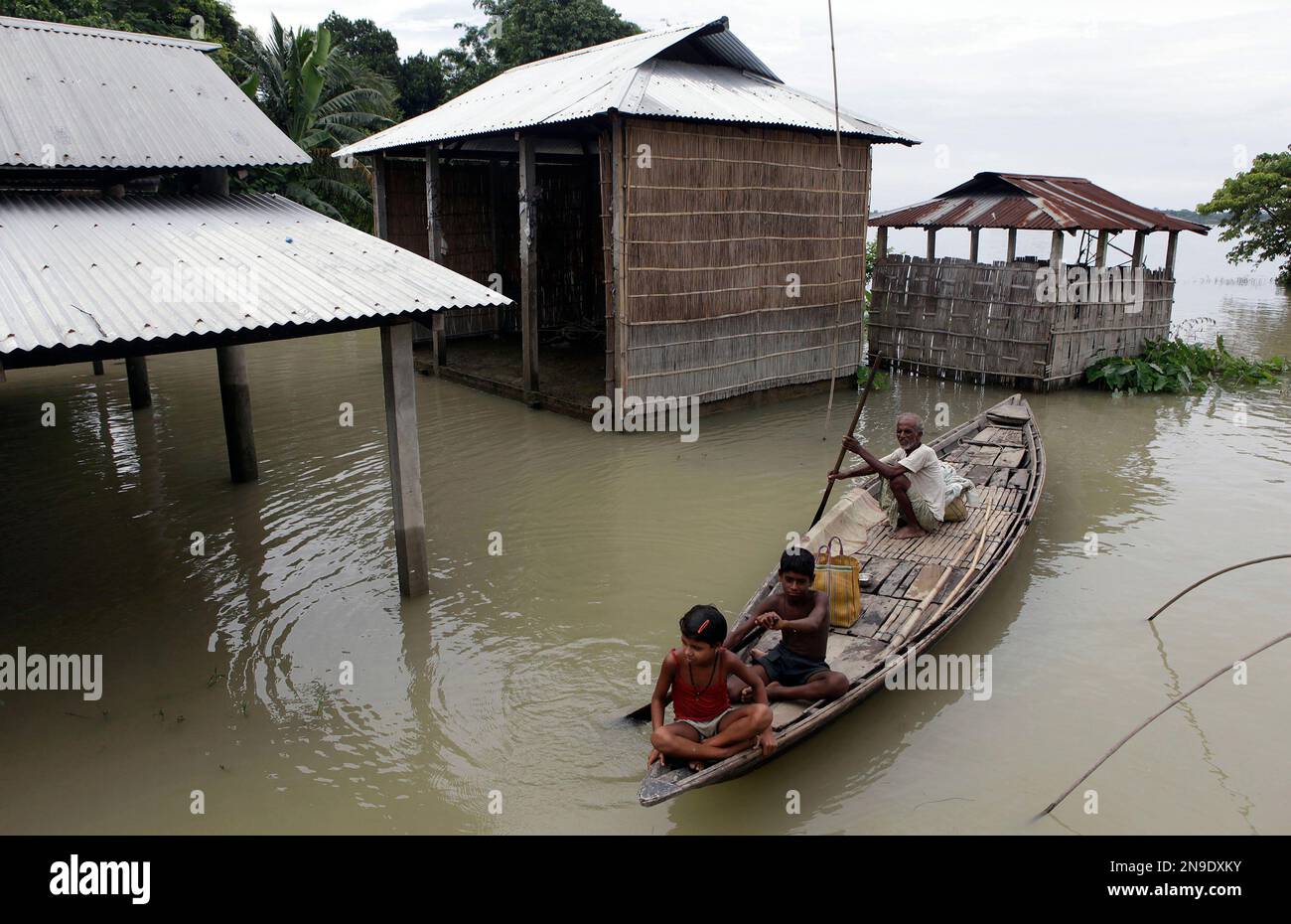 Flood affected children row a boat with an elderly man at Burhaburhi ...