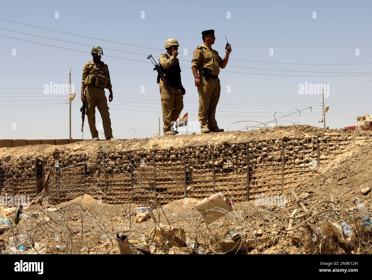 Iraqi soldiers stand guard in Qaim, located in the Euphrates river ...