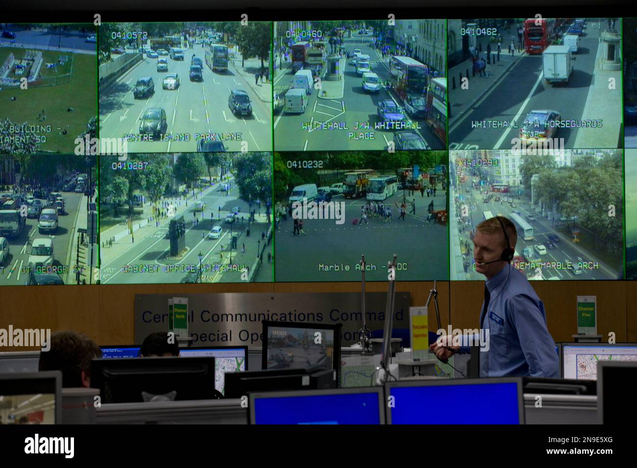 A member of police staff stands in front of CCTV screens in London's ...