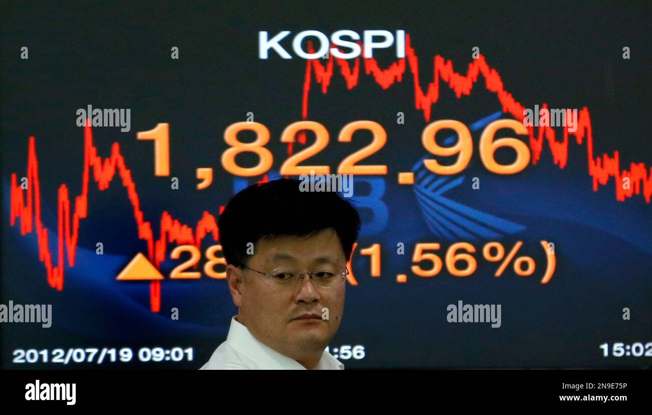 A currency trader passes by a screen showing the Korea Composite Stock ...