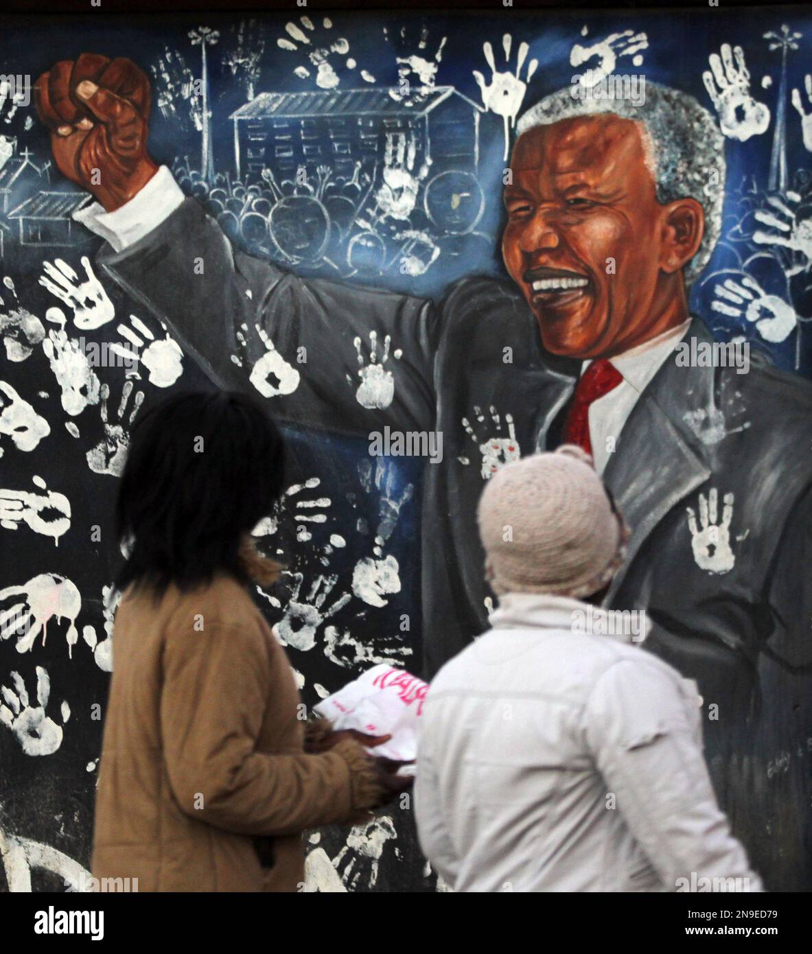 Two women walk past a mural depicting former South African President ...