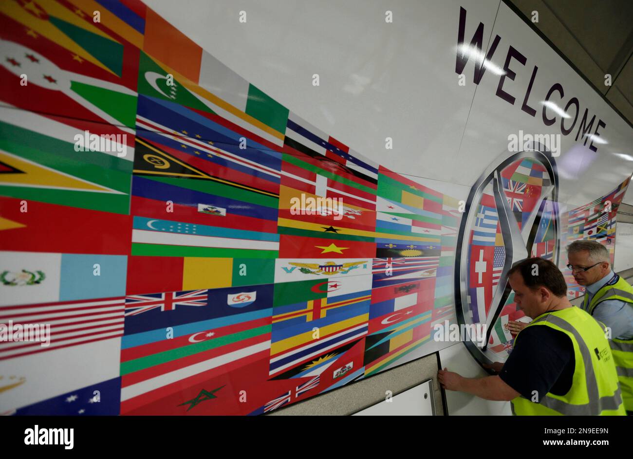 Workers erect a sign welcoming visitors at Heathrow Airport, Tuesday ...