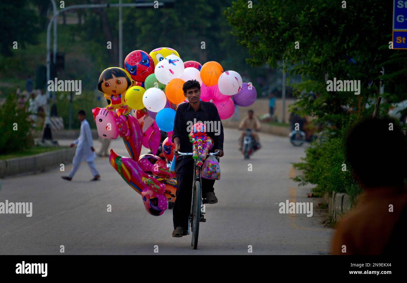 A Pakistani balloon seller rides his bike as he looks for customers at ...