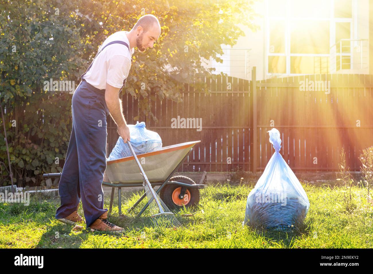 The gardener in the blue uniform is cleaning the yard.On the grass is a ...