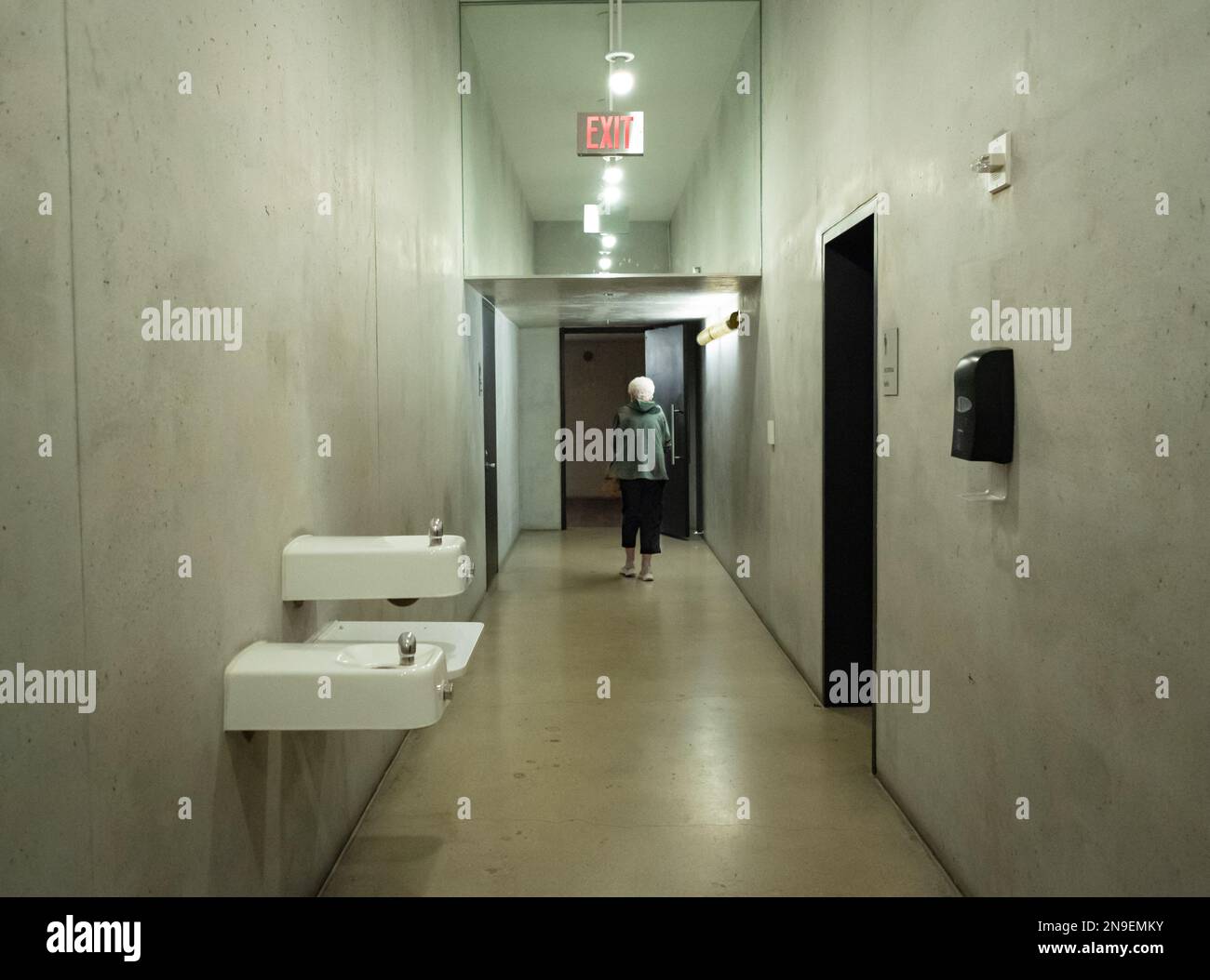 Eerie photo of a generic concrete bathroom hallway with drinking ...