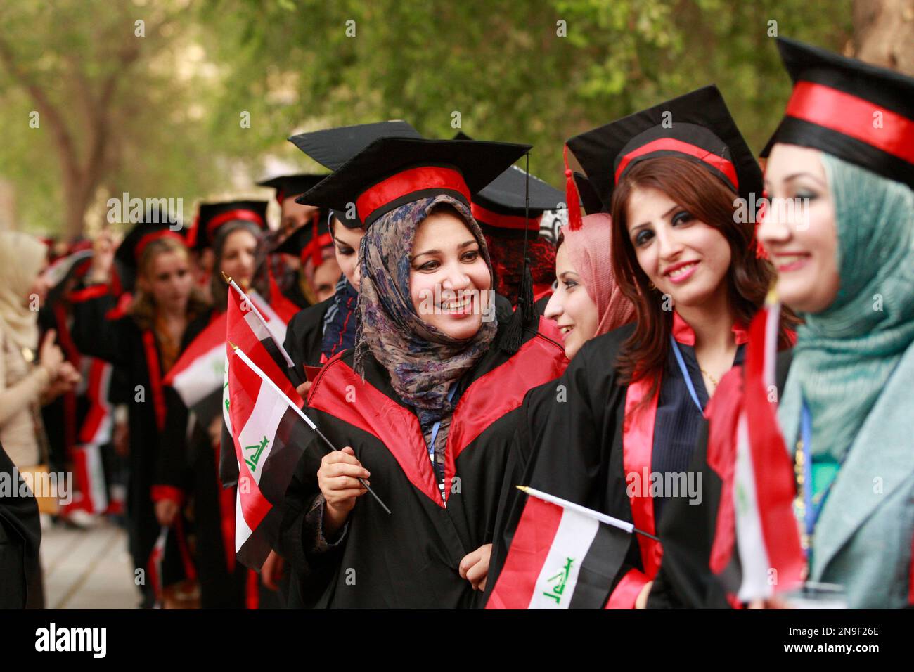 Graduates hold national flags as they celebrate during a graduation ...