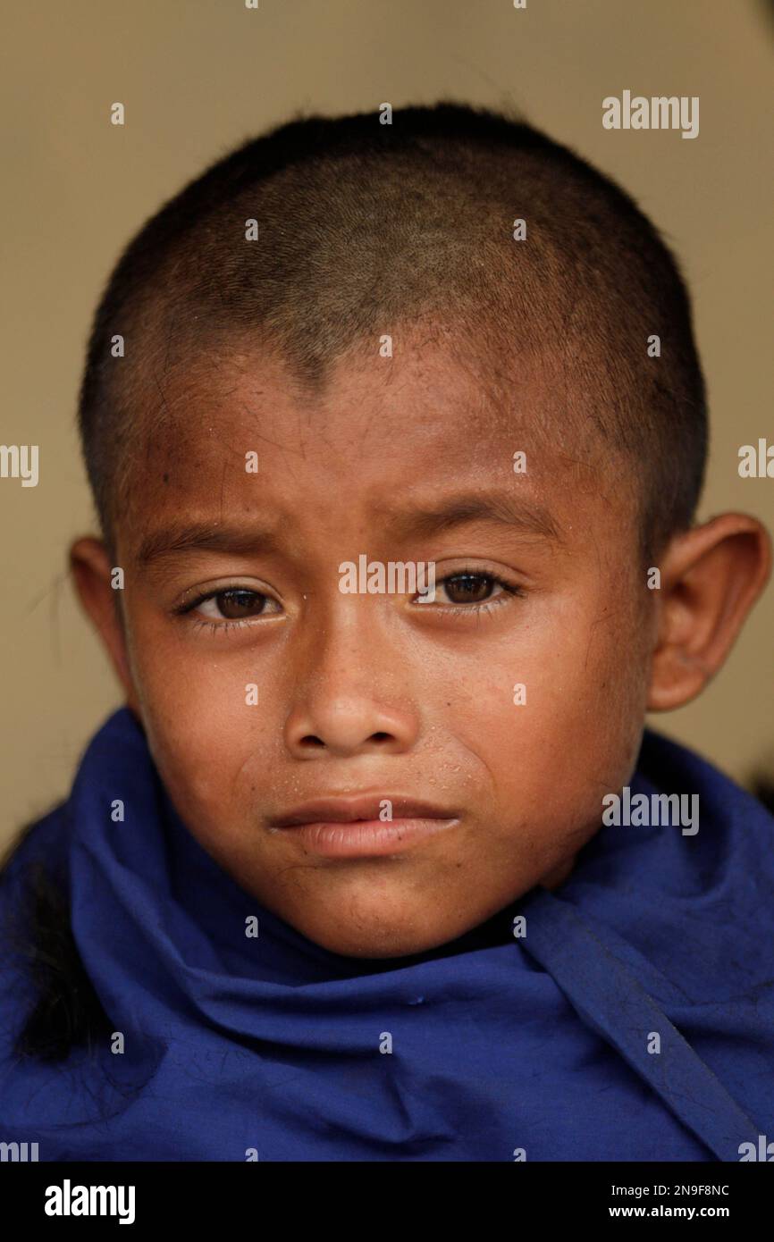 A Kuna Indigenous boy looks at the camera as he has his hair cut in ...