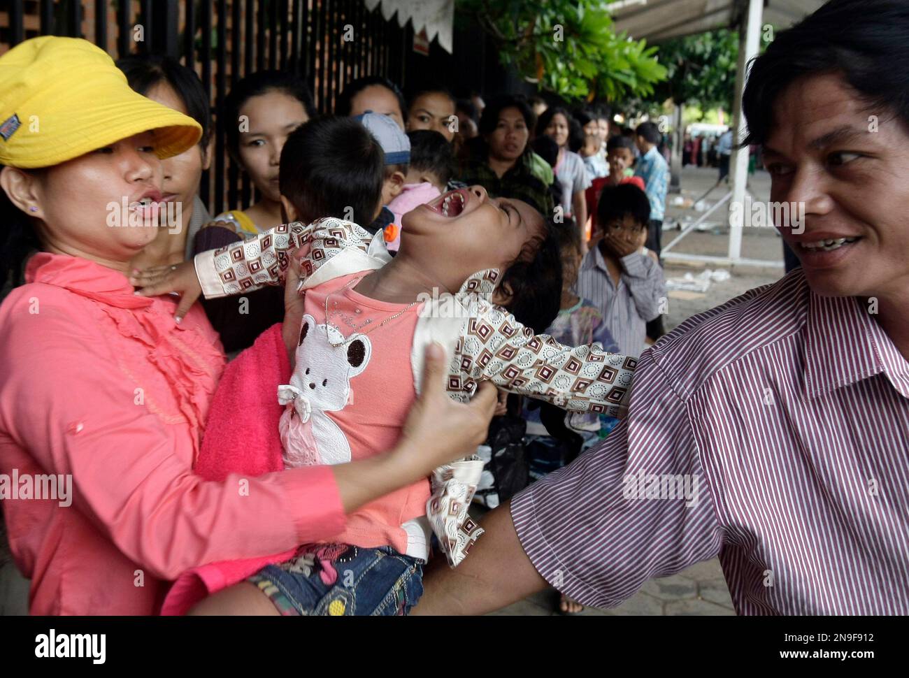 A girl cries while villagers line up to wait for a medical check-up for children outside Kuntha ...