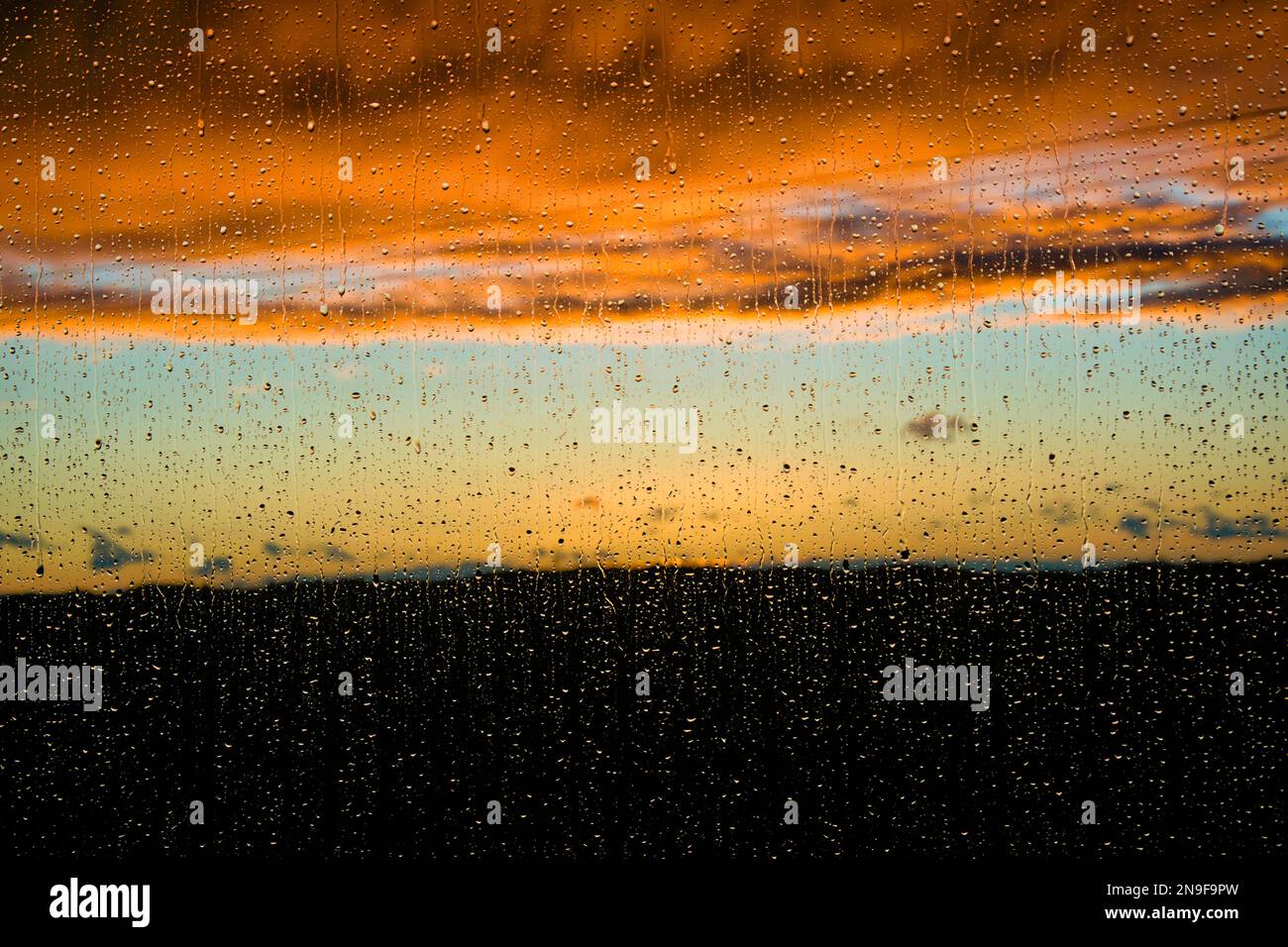 Sunset under the rain through the window with orange clouds Stock Photo ...