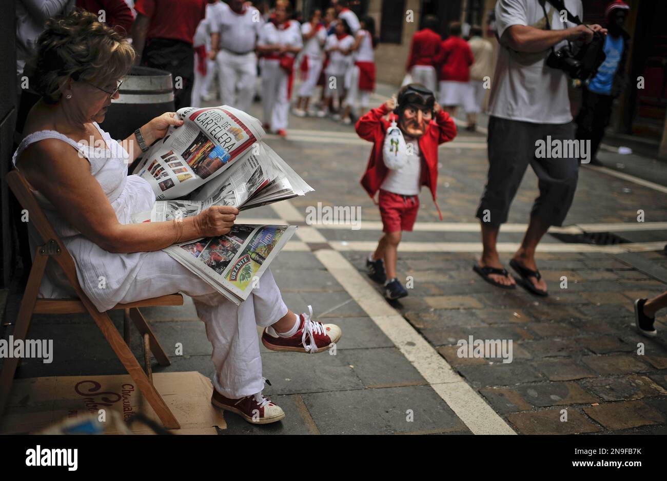 A young boy wears a mask of a San Fermin Cabezudos, a costumed figure ...
