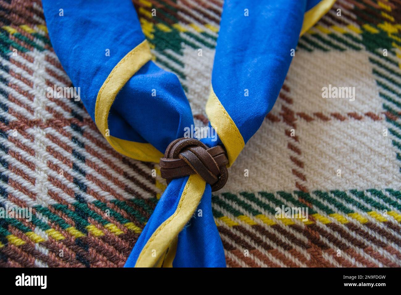 Blue with yellow border ABS scout scarf closed with scarf ring on brown ...