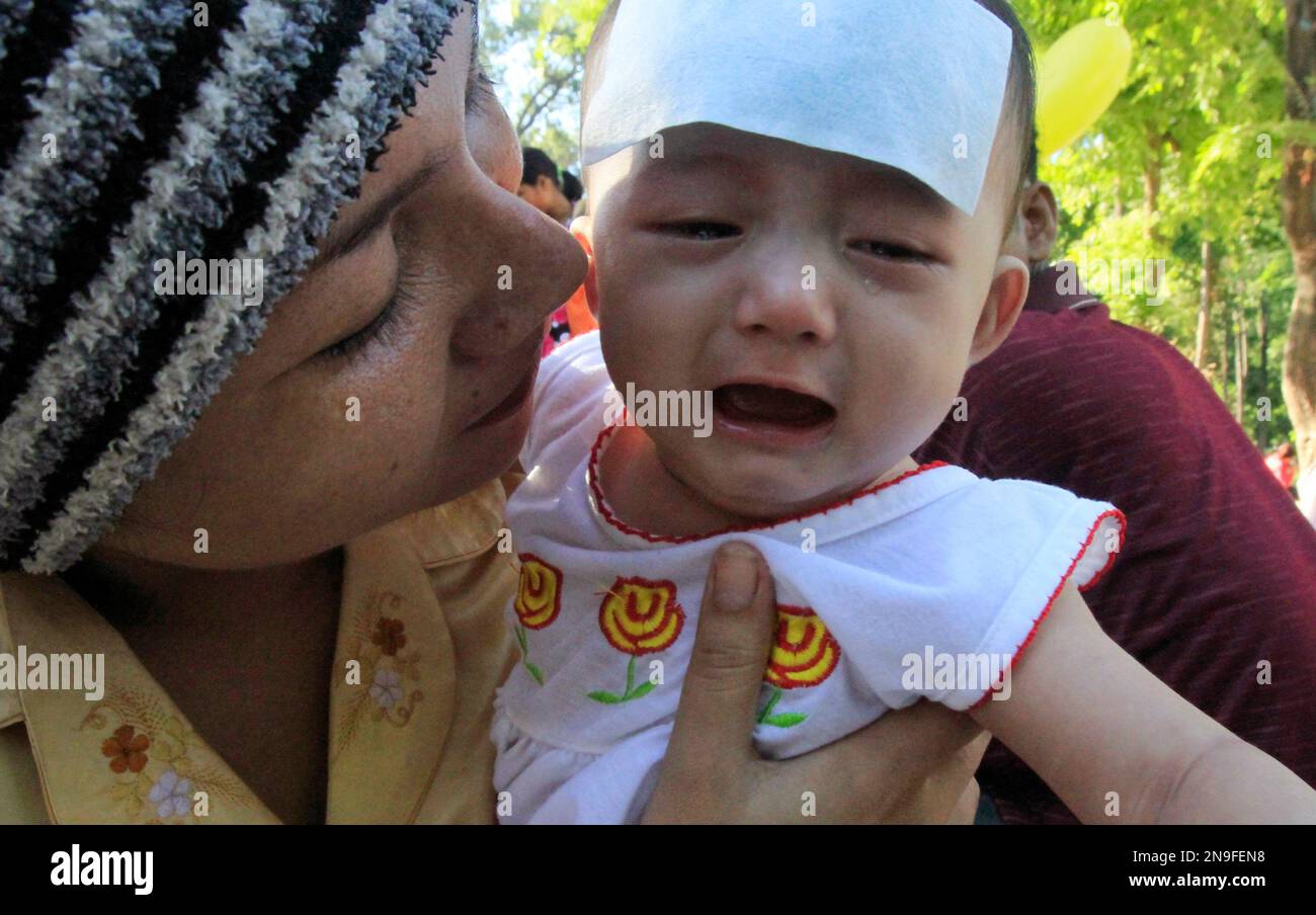 A Cambodian villager from countryside holds her baby as she waits for a medical check up for ...