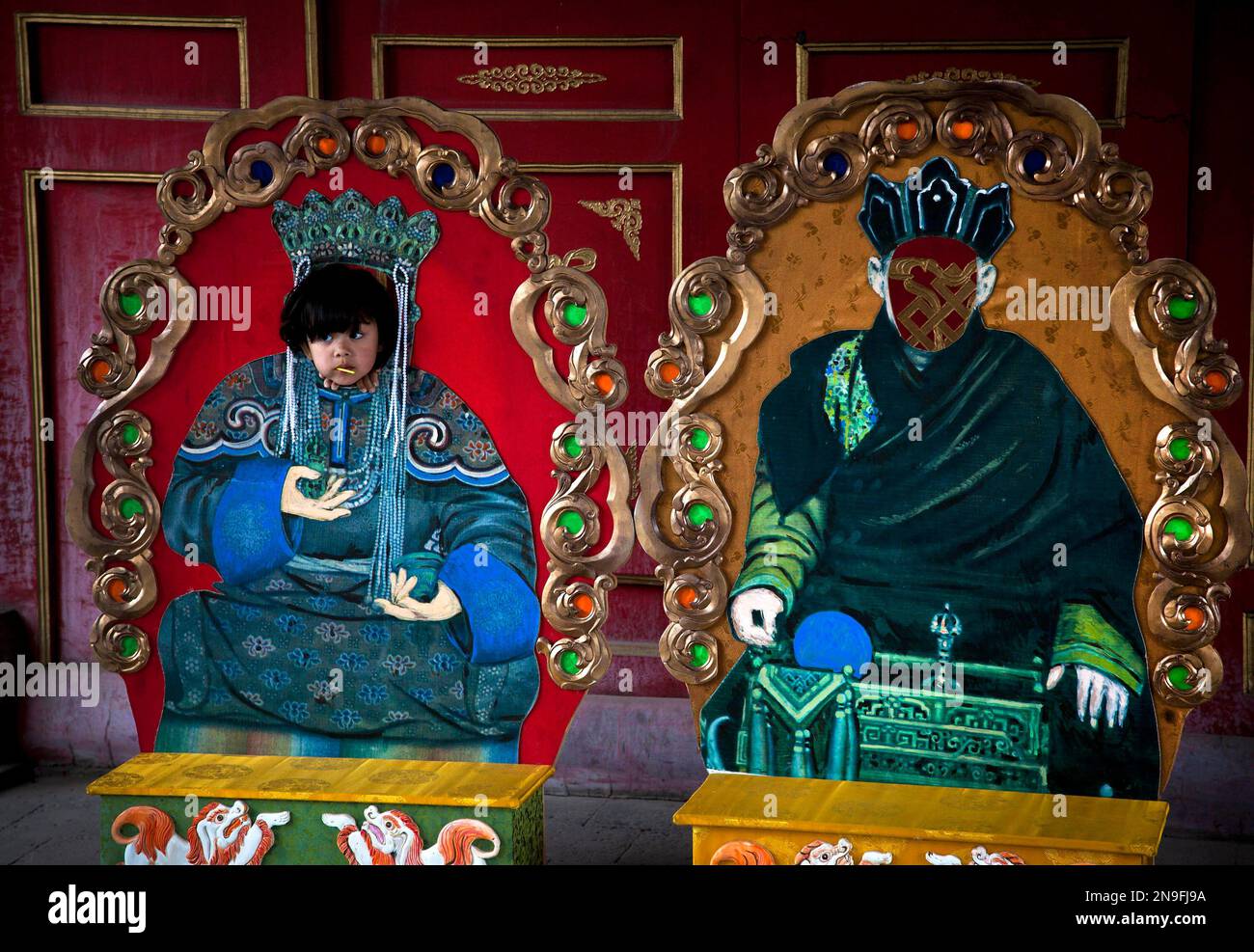 A Mongolian child plays on faceless Buddha cutouts set up for souvenir ...