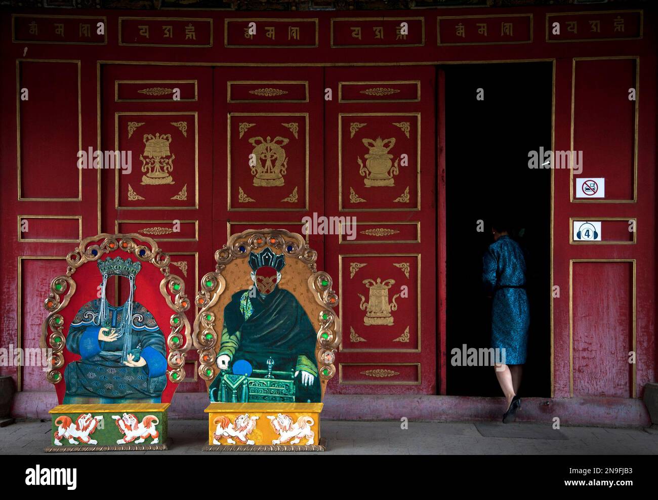 A Mongolian woman walks into a hall where faceless Buddha cutouts set ...