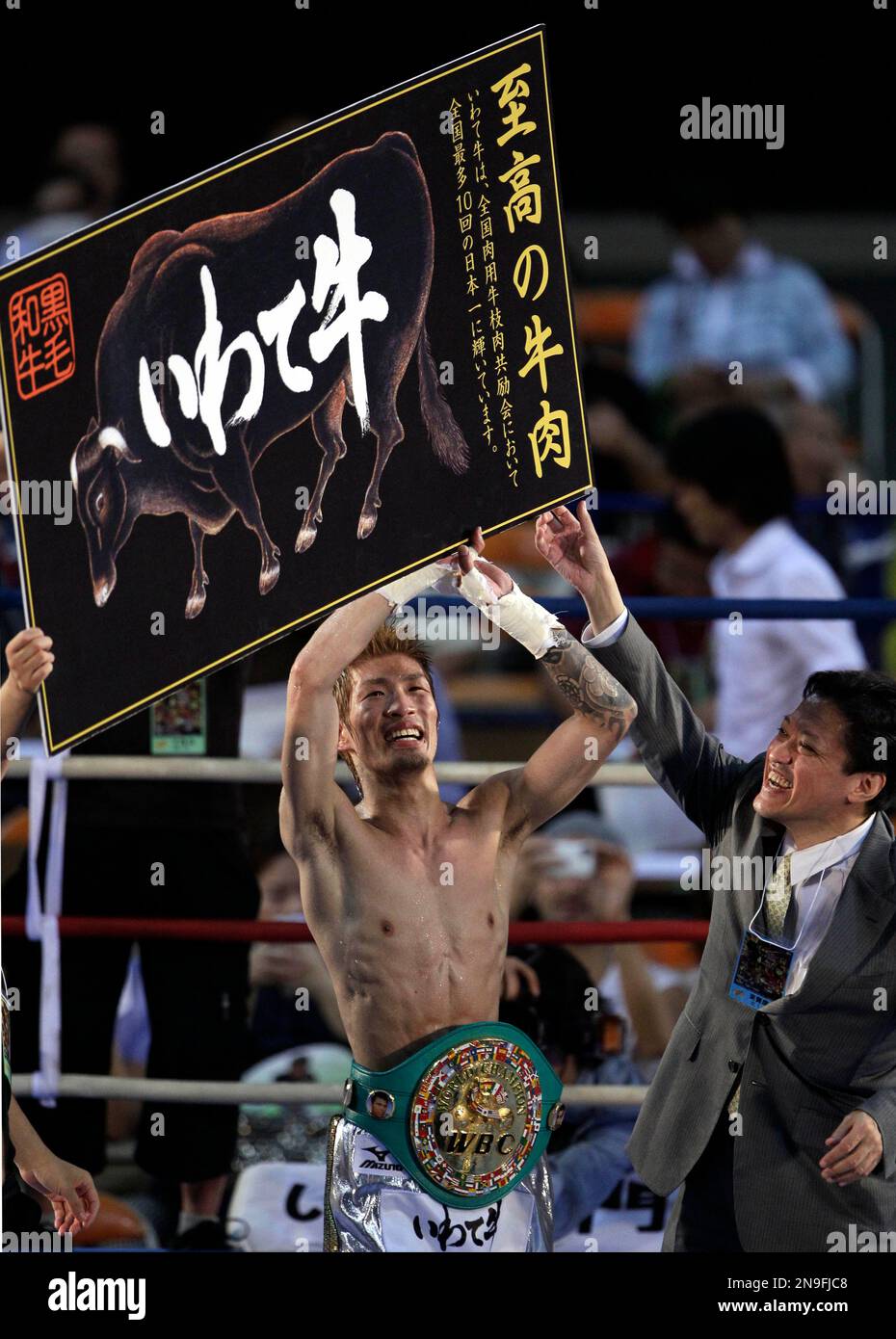 Japanese boxer Yota Sato wearing his champion belt holds up an award of ...