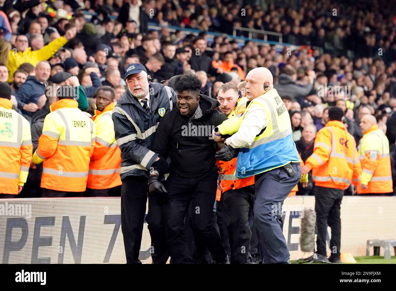 A fan is escorted off the pitch by stewards after the first goal by ...