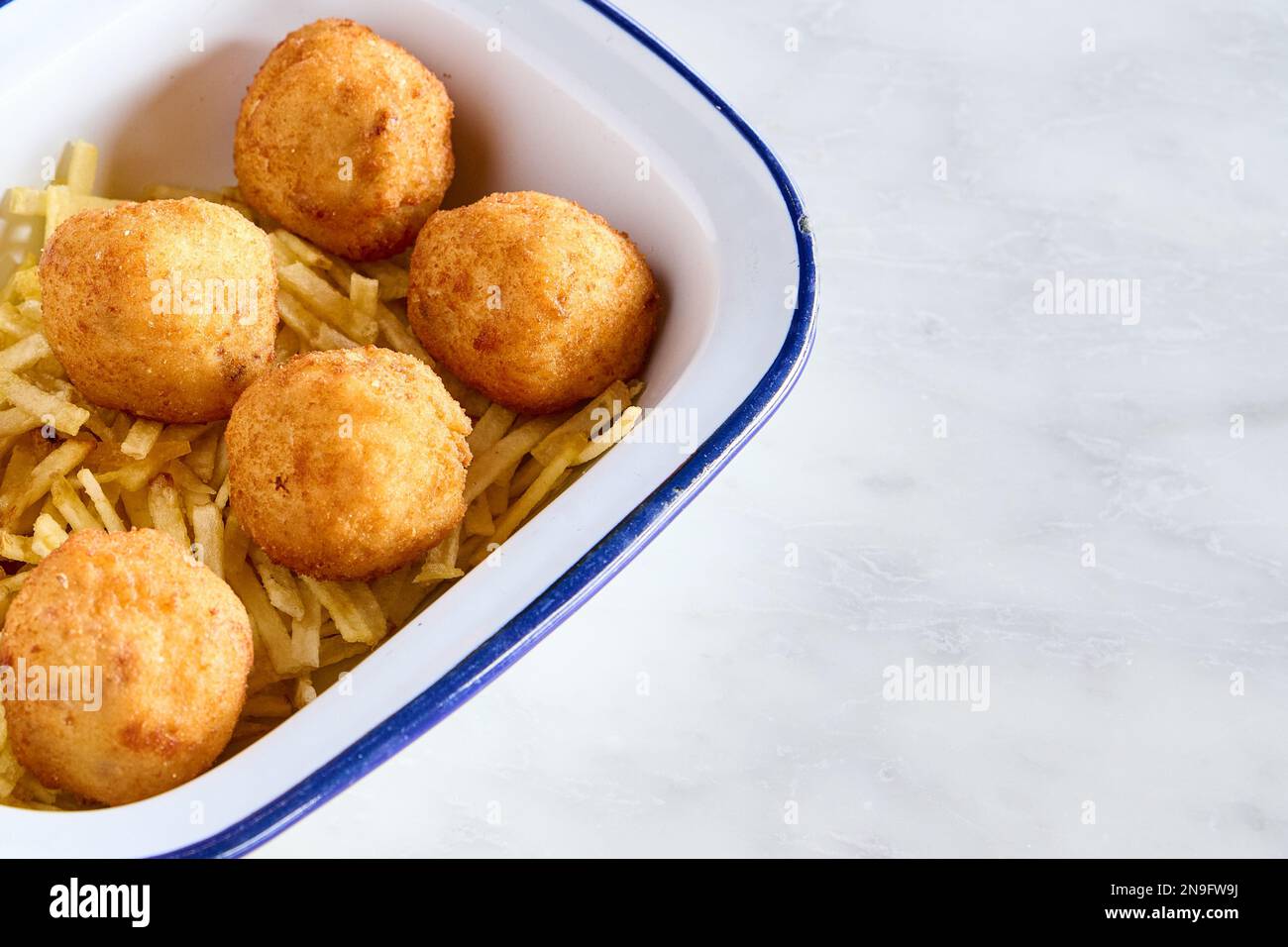 A top view closeup of fried cheese balls on little potato chips in a ...