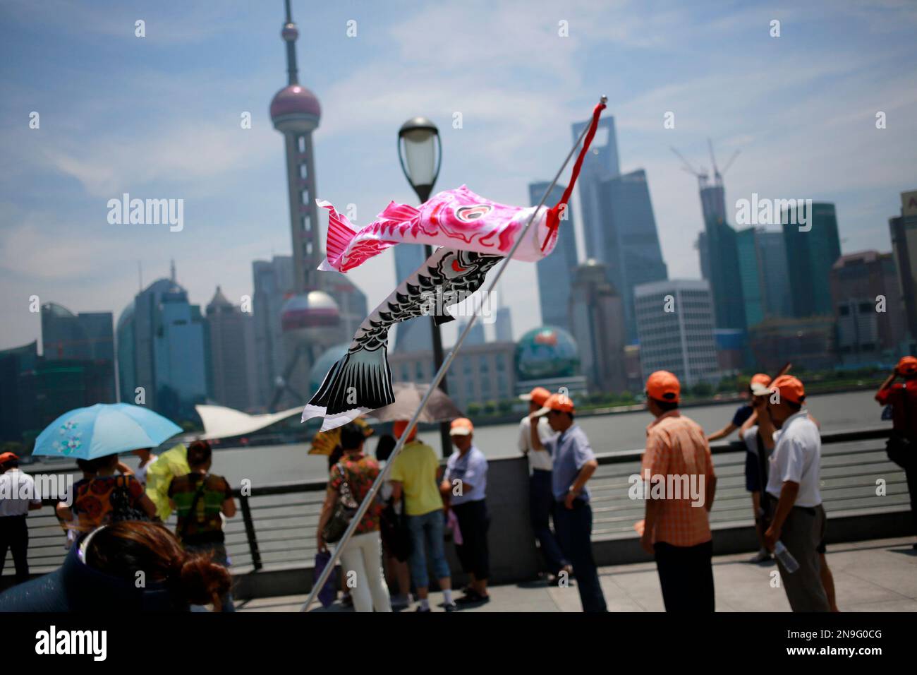 A tour guide hoists carp streamers to signal her customers at the Bund ...
