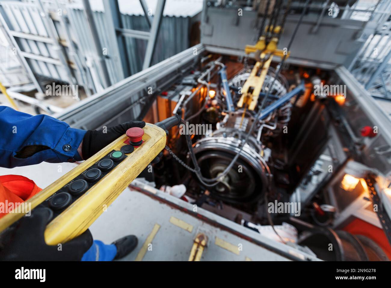 The engine of a gas turbine compressor hangs on a crane during installation in a module for ...