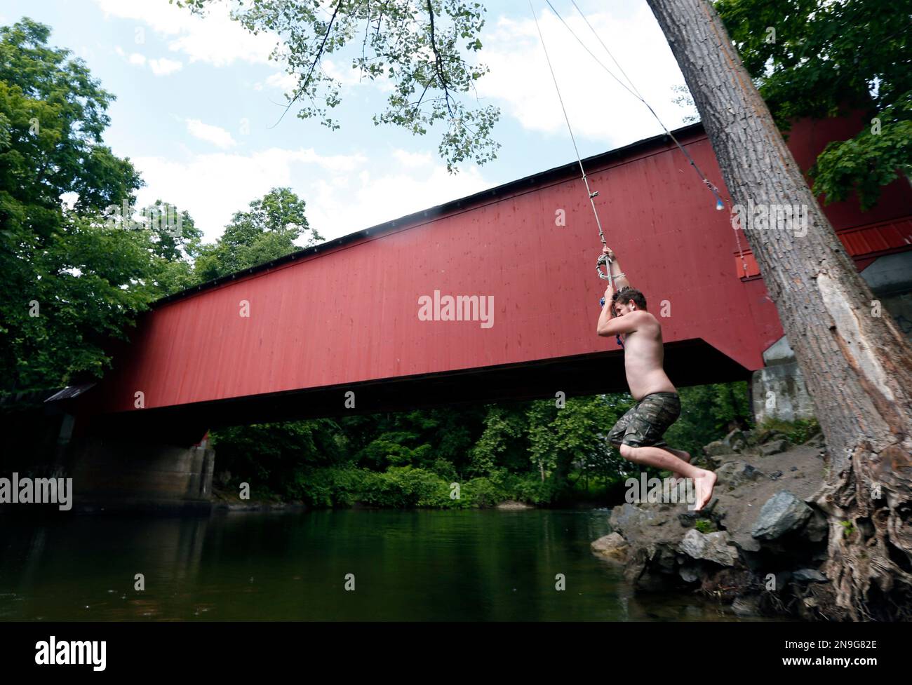 Nathan Bauscher of Cambridge, N.Y., swings on a rope before jumping into the Battenkill River in ...