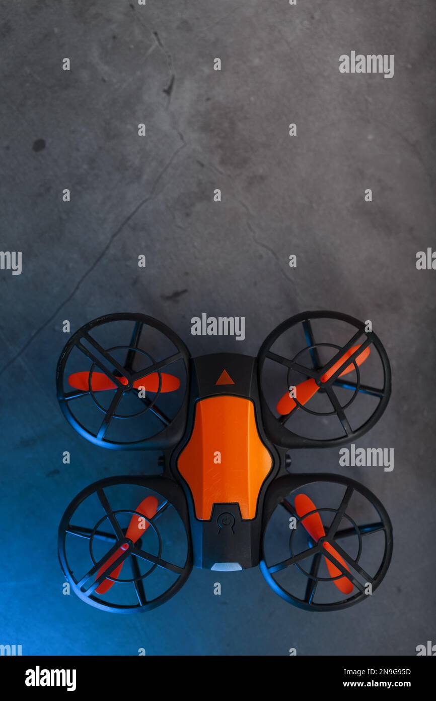 Orange quadcopter mini spy drone on a dark background with blue ...