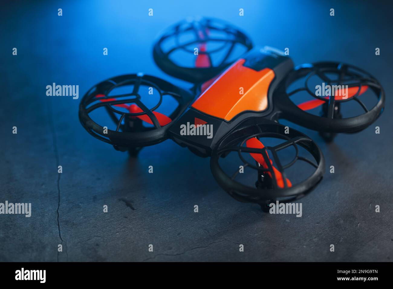 Orange quadcopter mini spy drone on a dark background with blue ...