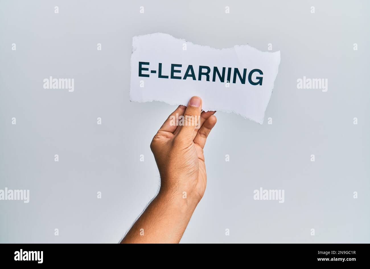 Hand of caucasian man holding paper with e-learning word over isolated white background Stock ...