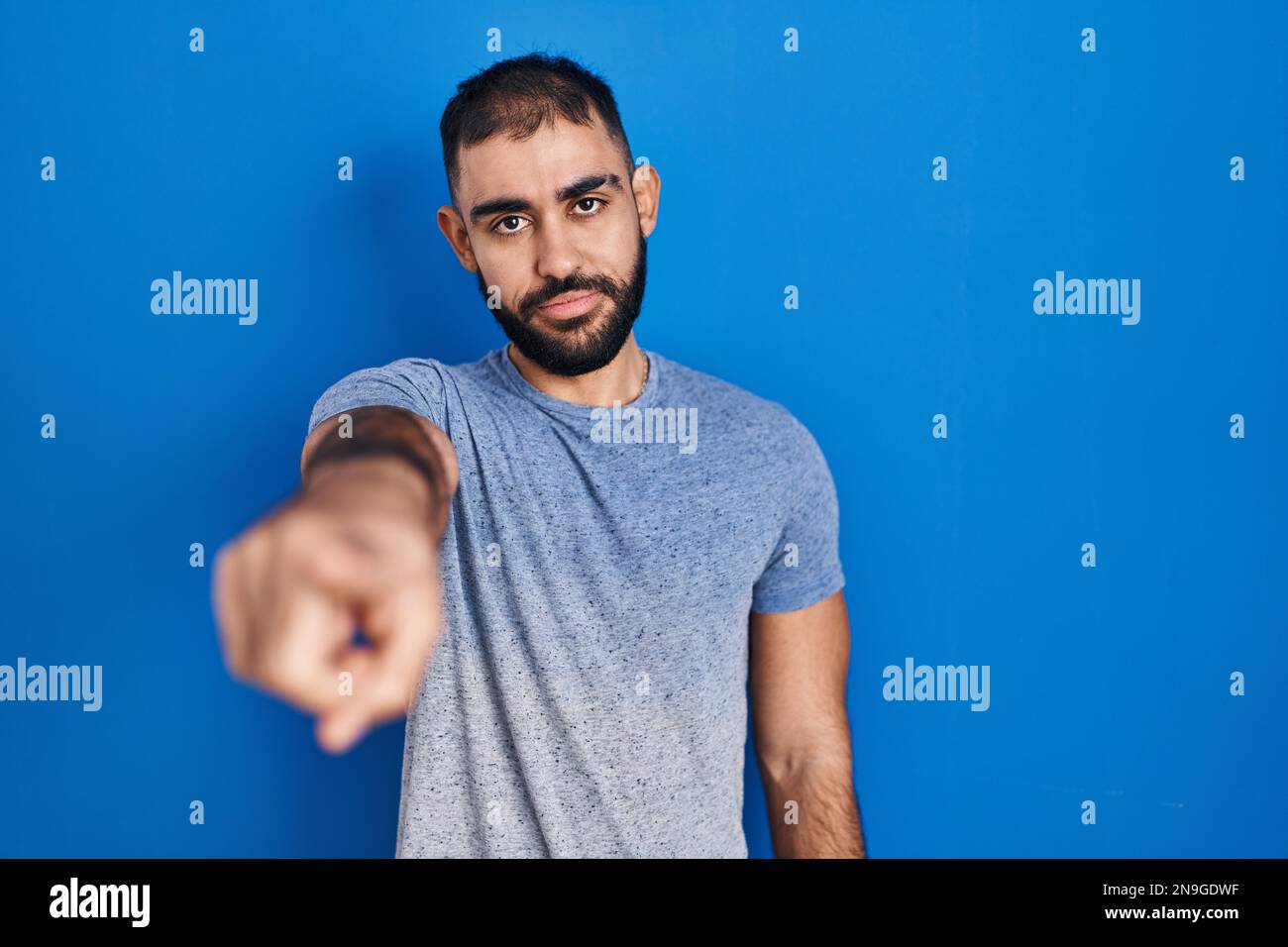 Middle east man with beard standing over blue background pointing ...