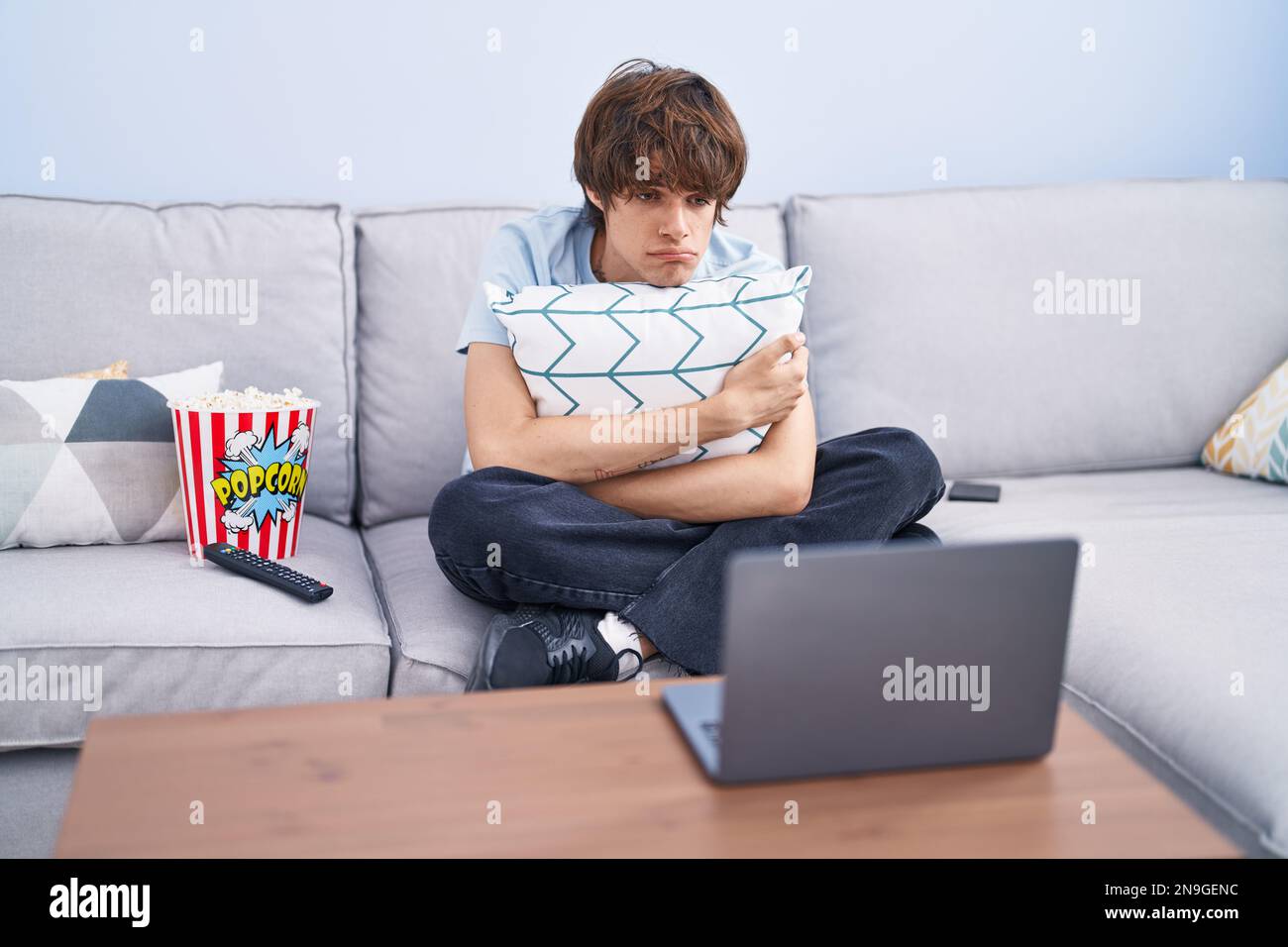 Hispanic young man watching a horror movie in the laptop depressed and ...