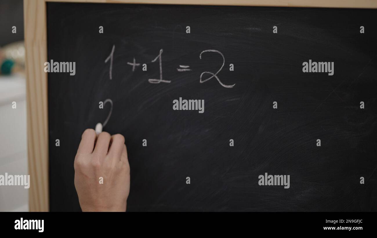 Young blonde woman preschool teacher writing maths exercise on ...