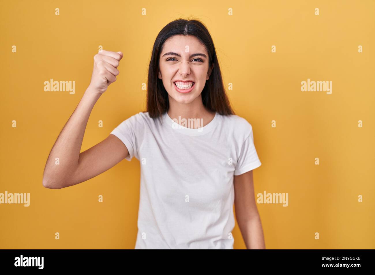 Young beautiful woman standing over yellow background angry and mad ...