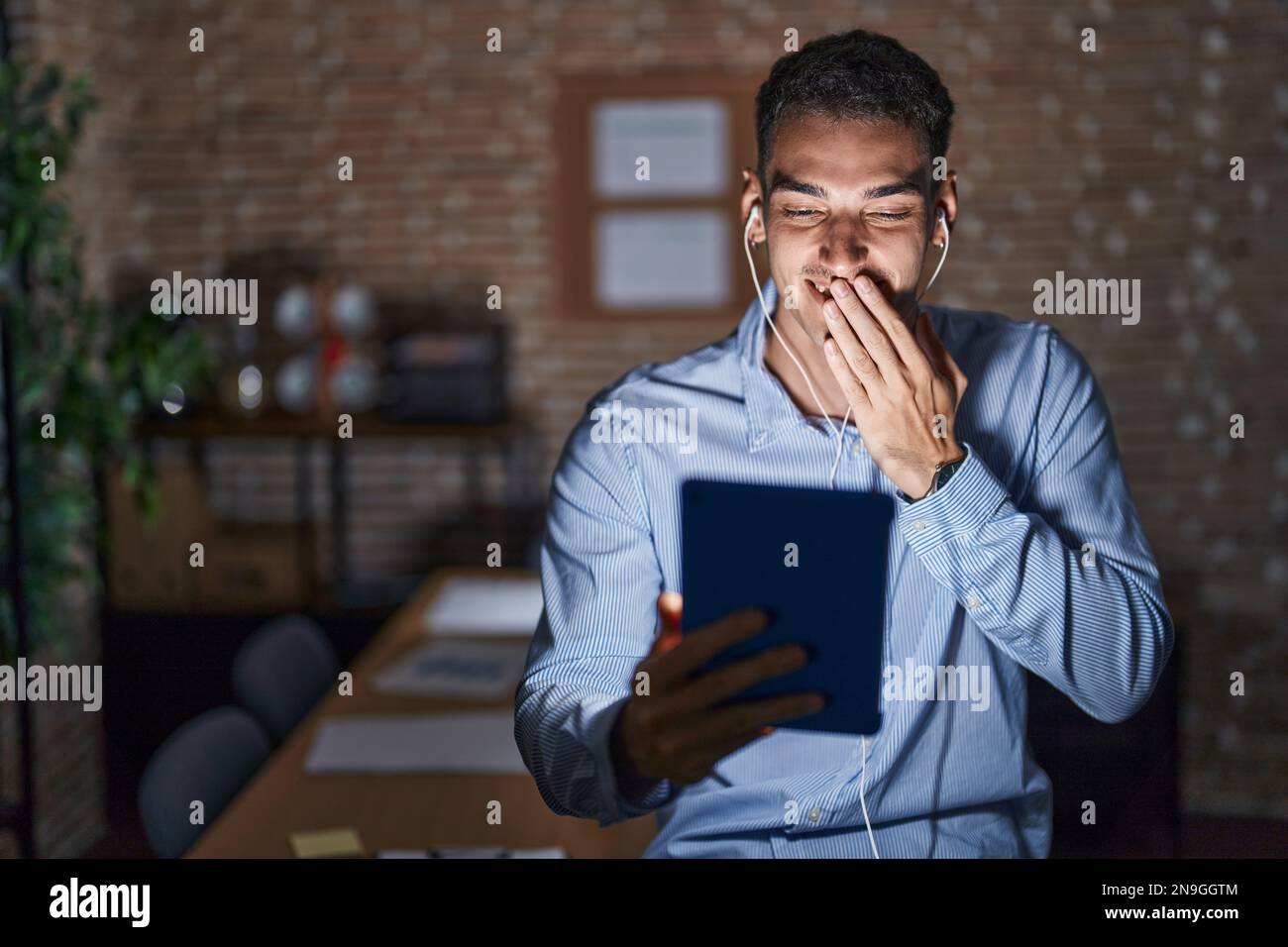 Handsome hispanic man working at the office at night laughing and ...