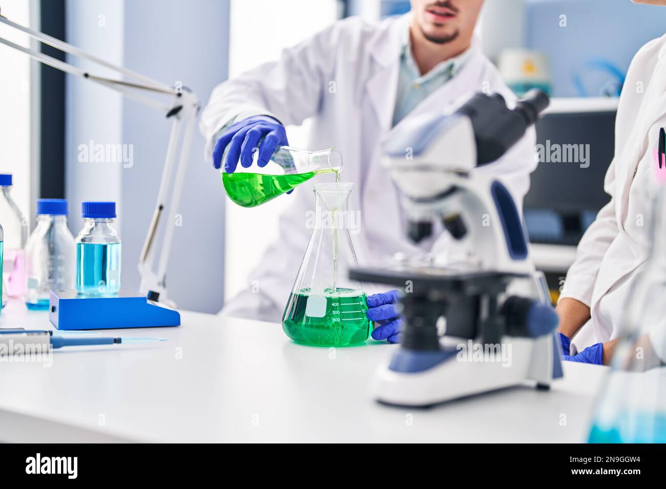Young man and woman scientists workers measuring liquid at laboratory ...