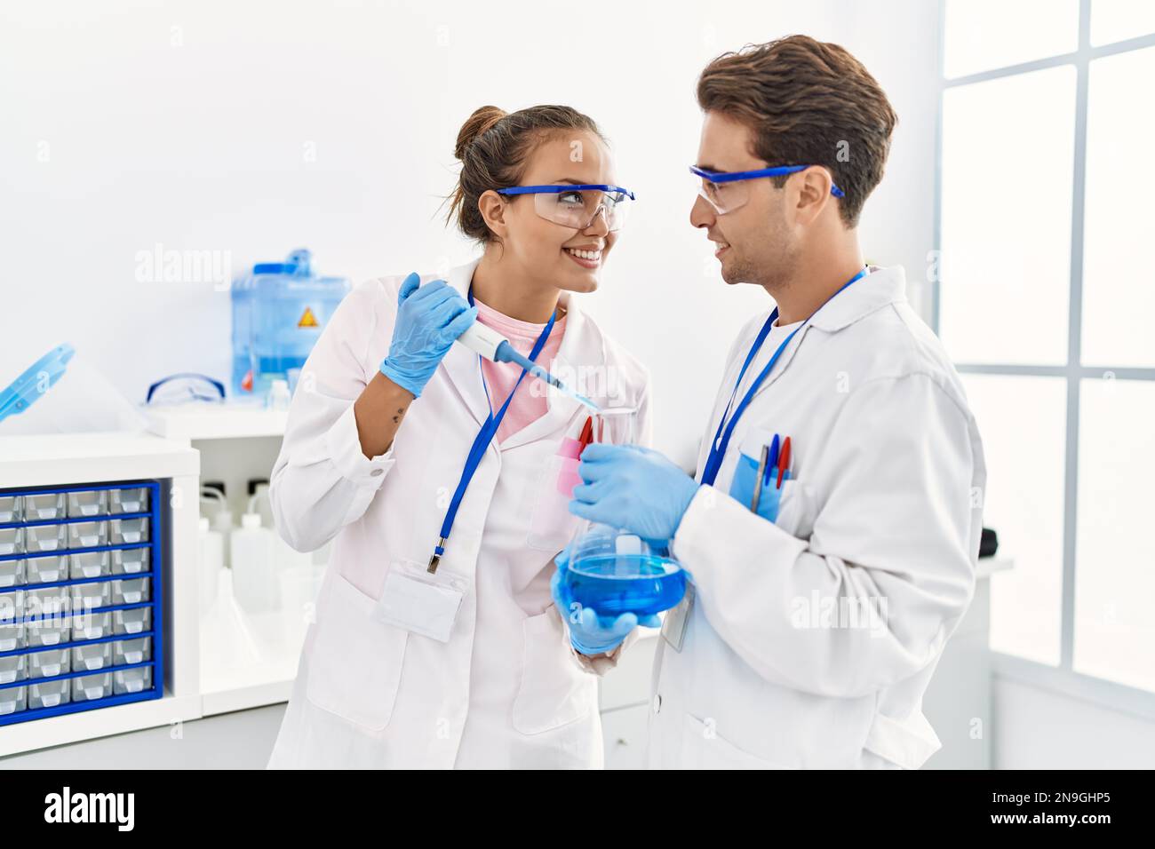 Man and woman wearing scientist uniform using pipette and test tube ...