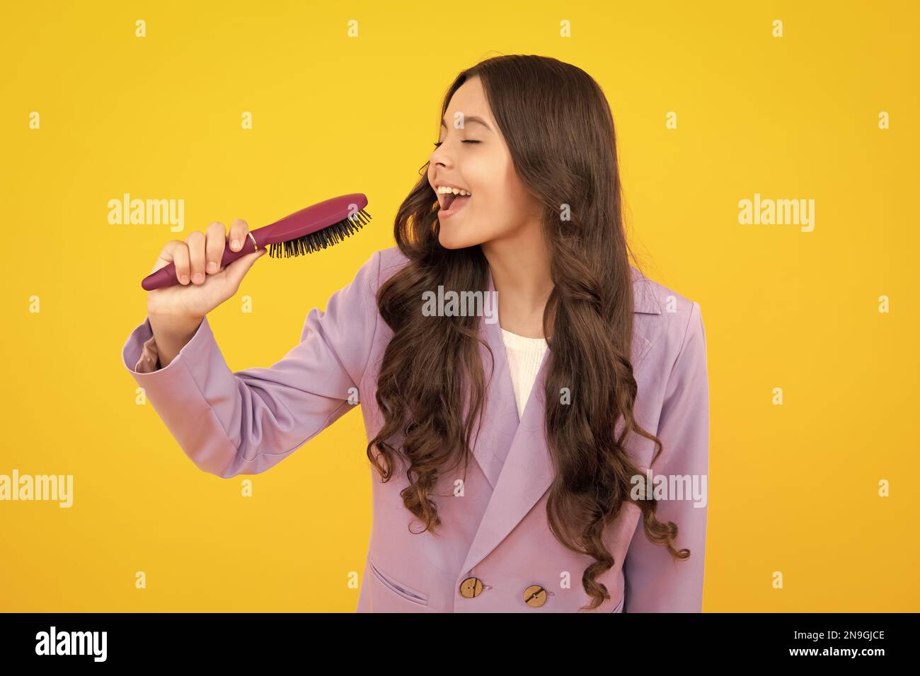 Excited fun teenager girl singing with comb. Child girl with brush ...