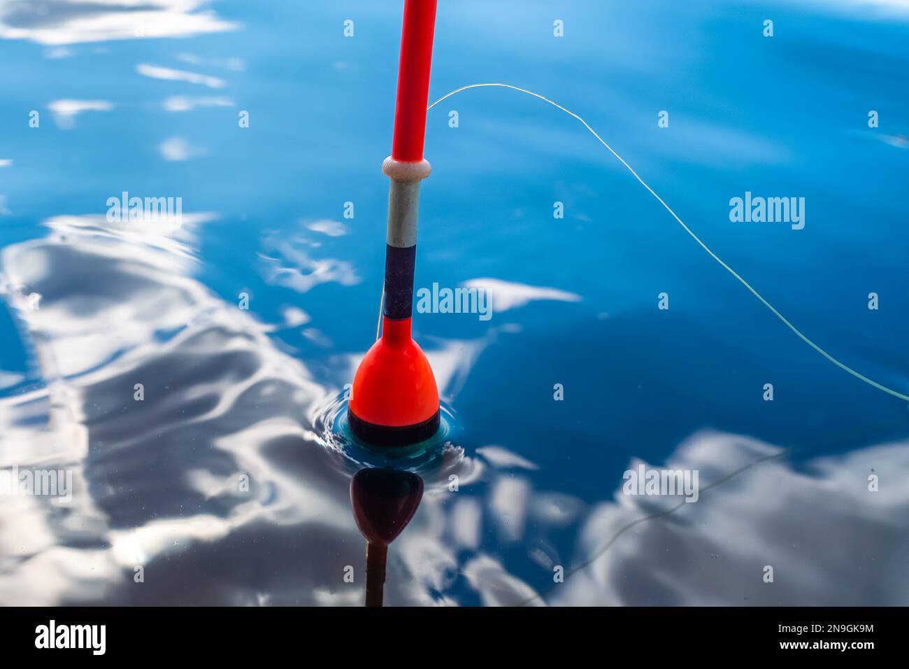 red fishing float floats on water in which clouds are reflected Stock ...