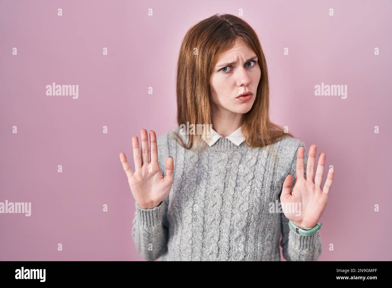 Beautiful woman standing over pink background moving away hands palms ...