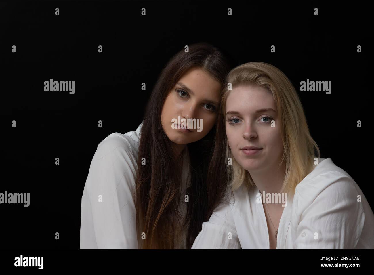 Low key portrait of beautiful two girls posing for the camera on the ...