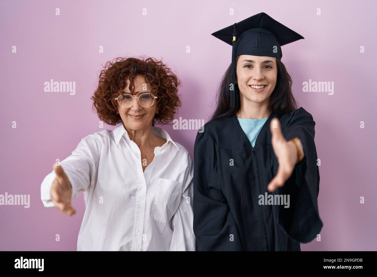 Hispanic mother and daughter wearing graduation cap and ceremony robe ...
